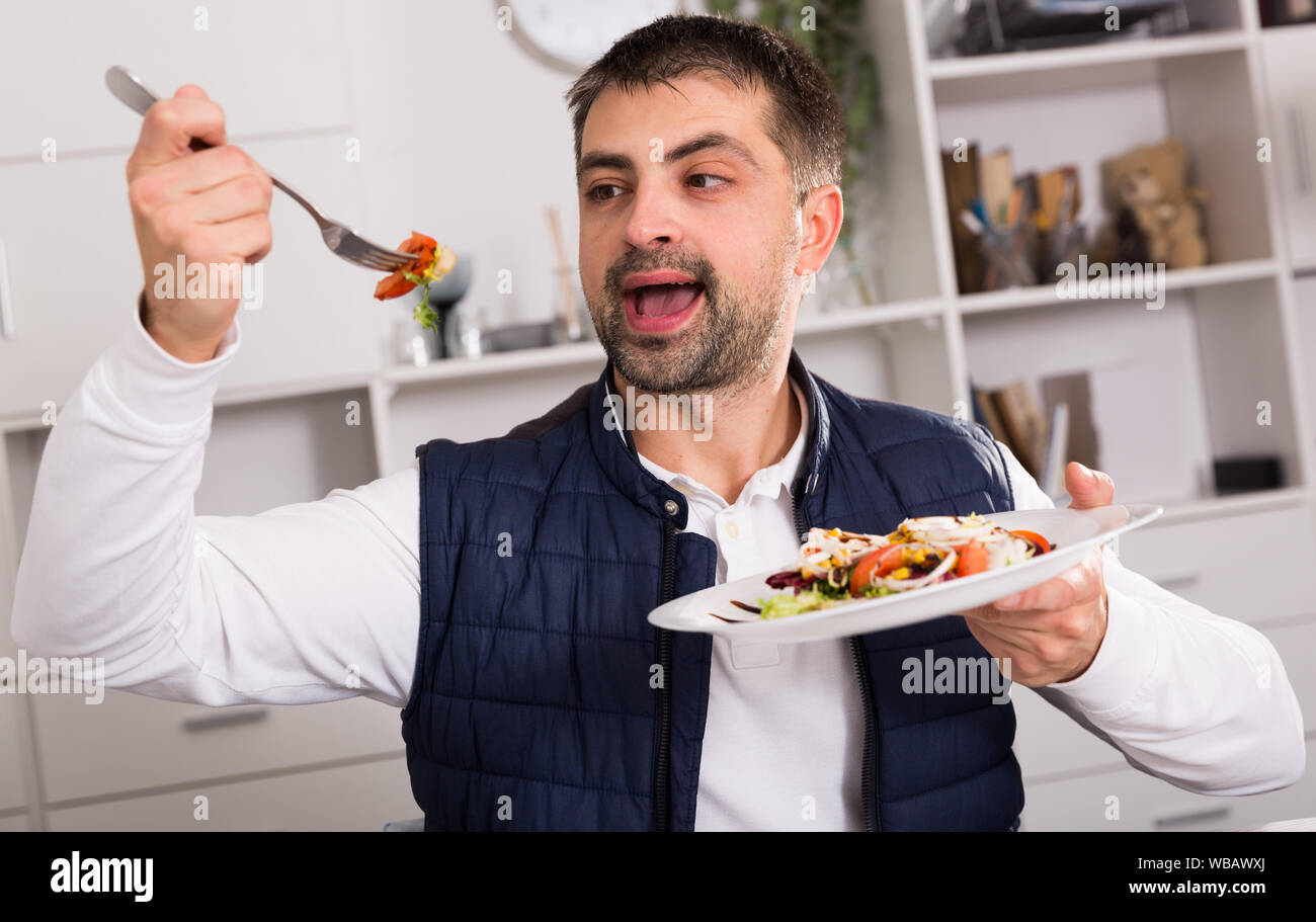 Portrait of young man eating vegetable salad and holding fork Stock ...