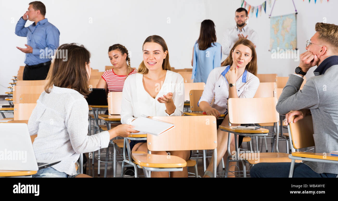 Happy group of adult students lively chatting while enjoying free time ...