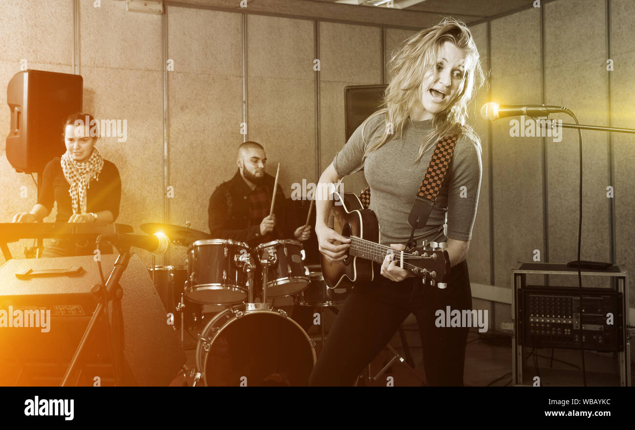 happy excited blonde girl rock singer with guitar during rehearsal with ...