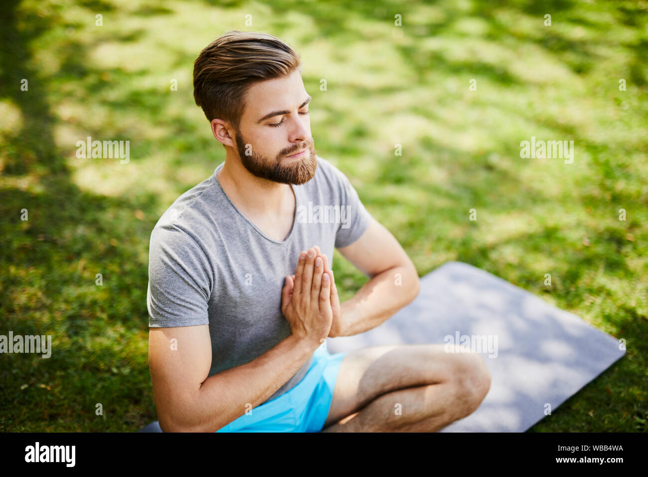 Portrait of meditating young man with his hands together and closed ...