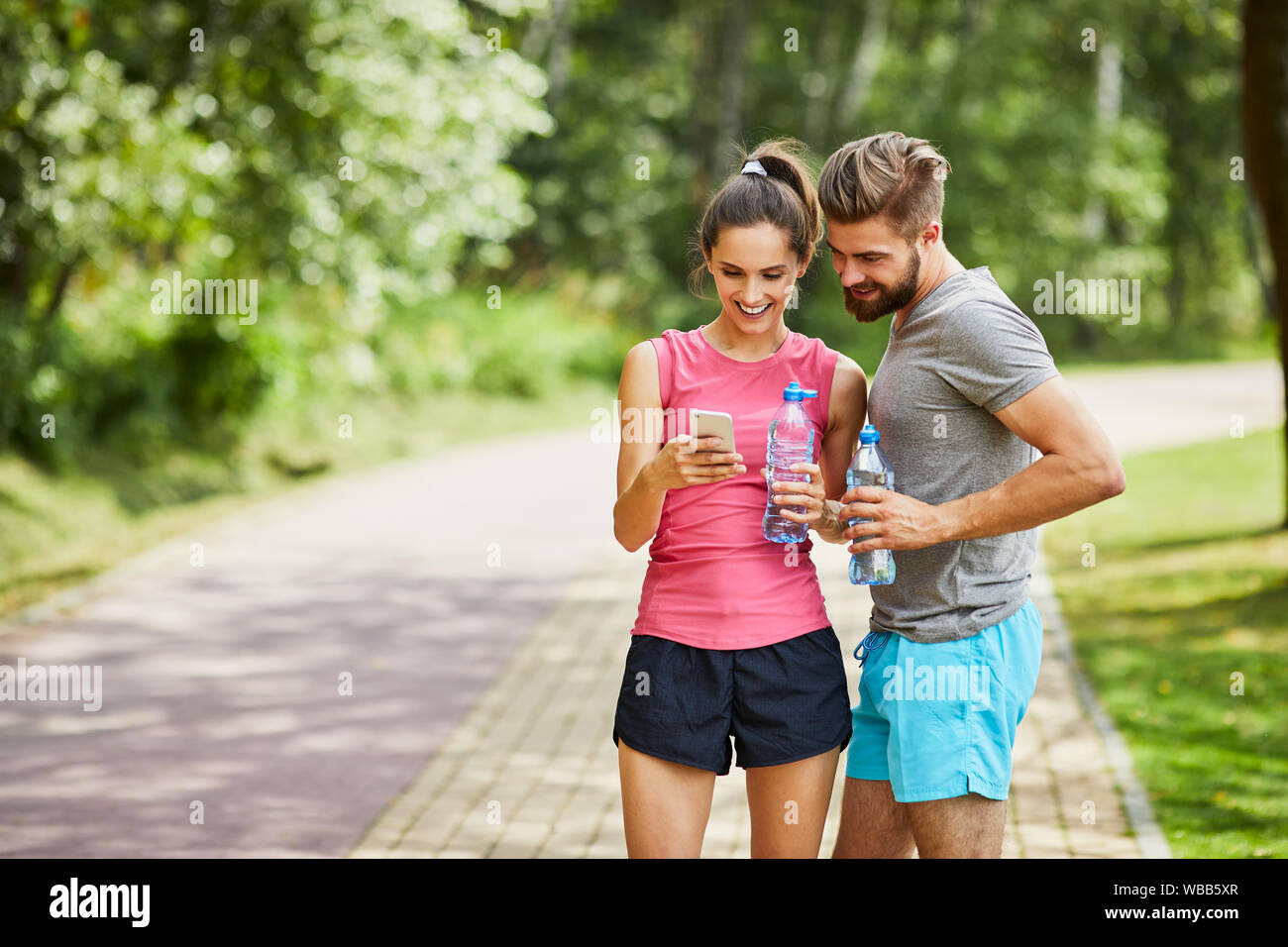 Young couple looking at phone while jogging in the summer Stock Photo ...
