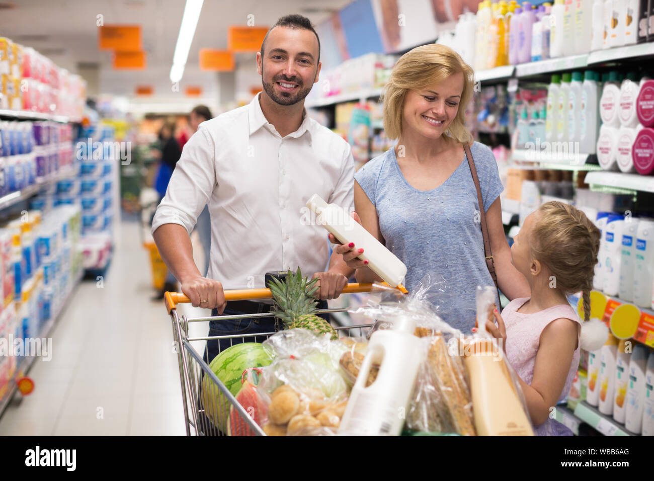Happy family with kid picking cleaning products in household section in ...