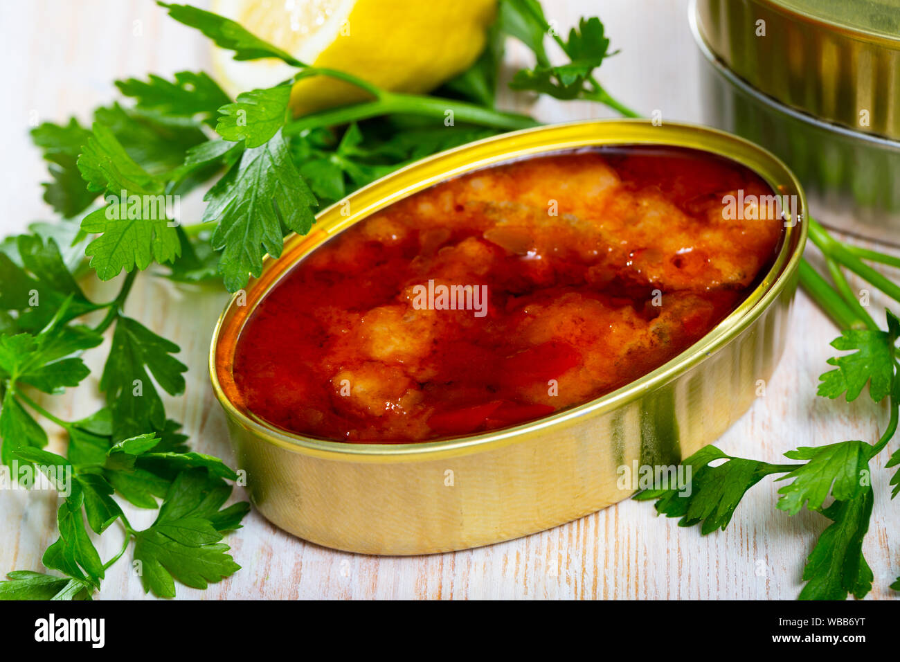 Deliciously tinned cod in tomato sauce on background with greens and ...