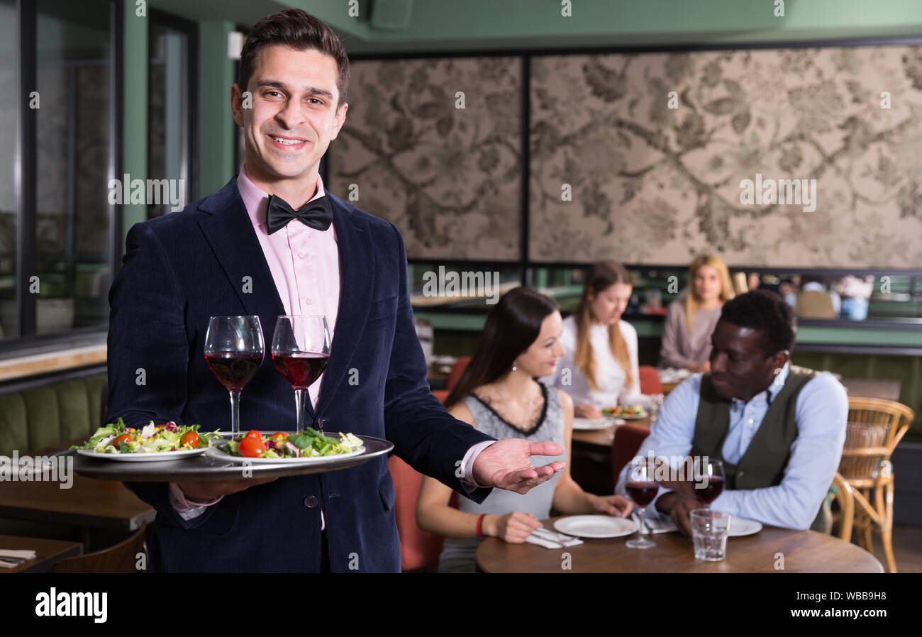 Handsome elegant waiter with serving tray welcoming to restaurant Stock ...