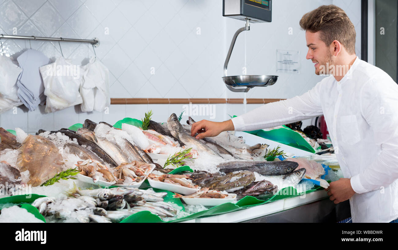 Young assistant helps to choose sea fish Stock Photo - Alamy