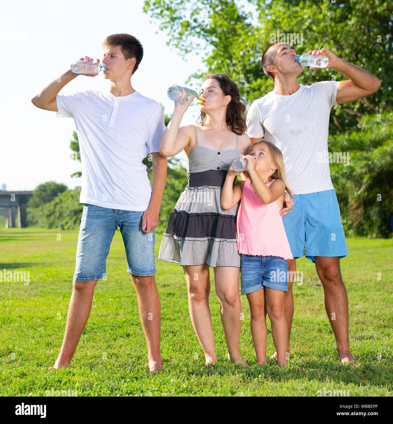 Young parents with children drinking clear bottled water during family ...