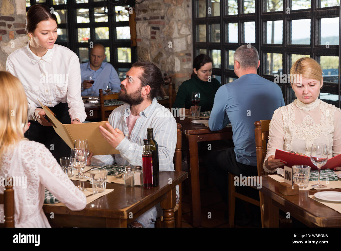 Young people sitting with menu card in rustic restaurant, discussing ...