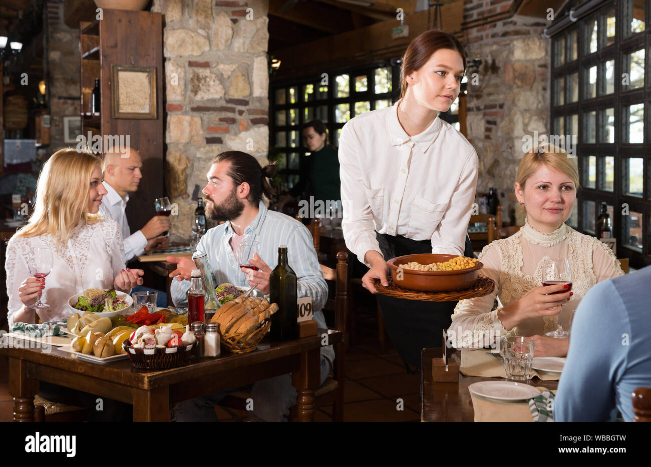 Young female waiter serving country restaurant guests Stock Photo - Alamy