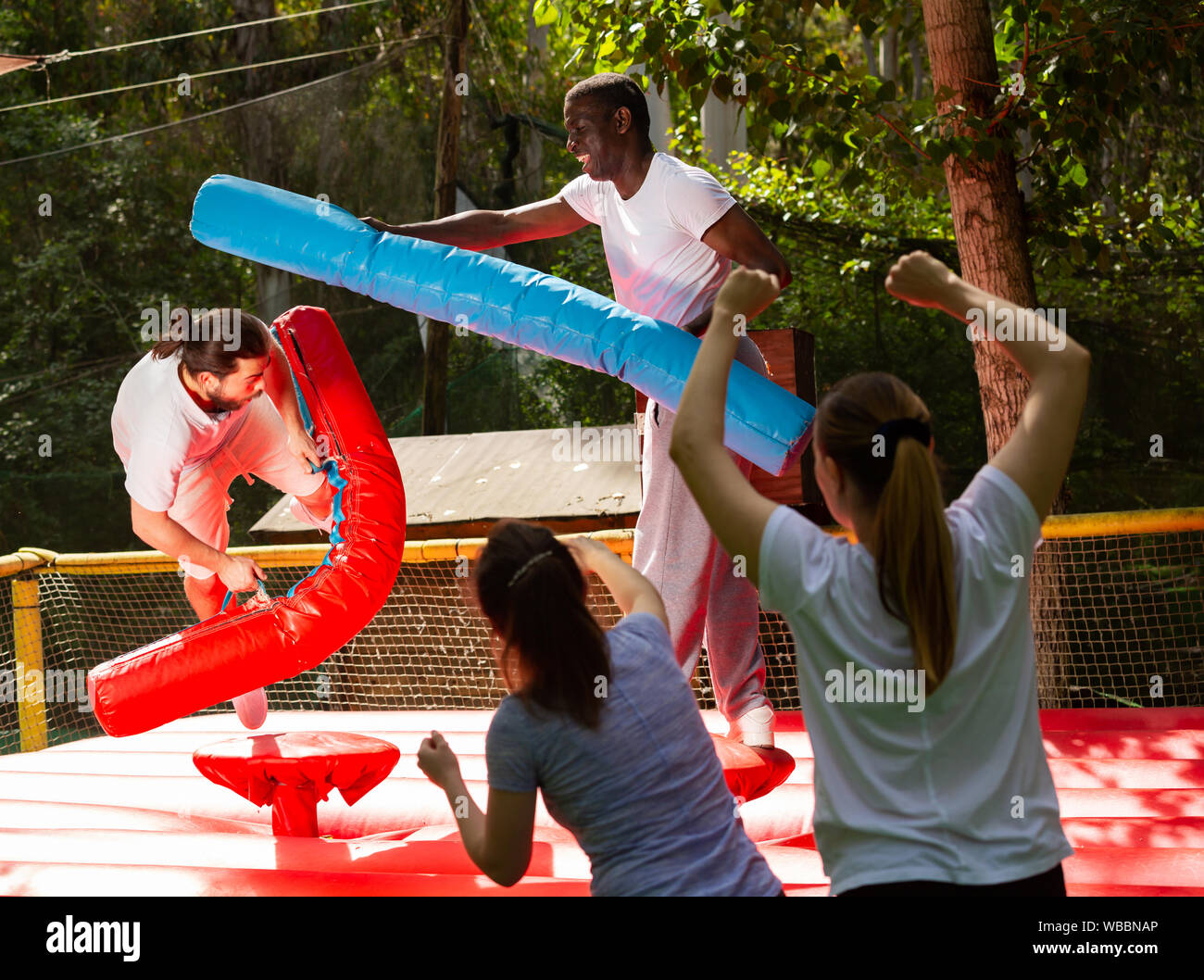 Cheerful adult men having fun on inflatable gladiator fight arena in ...