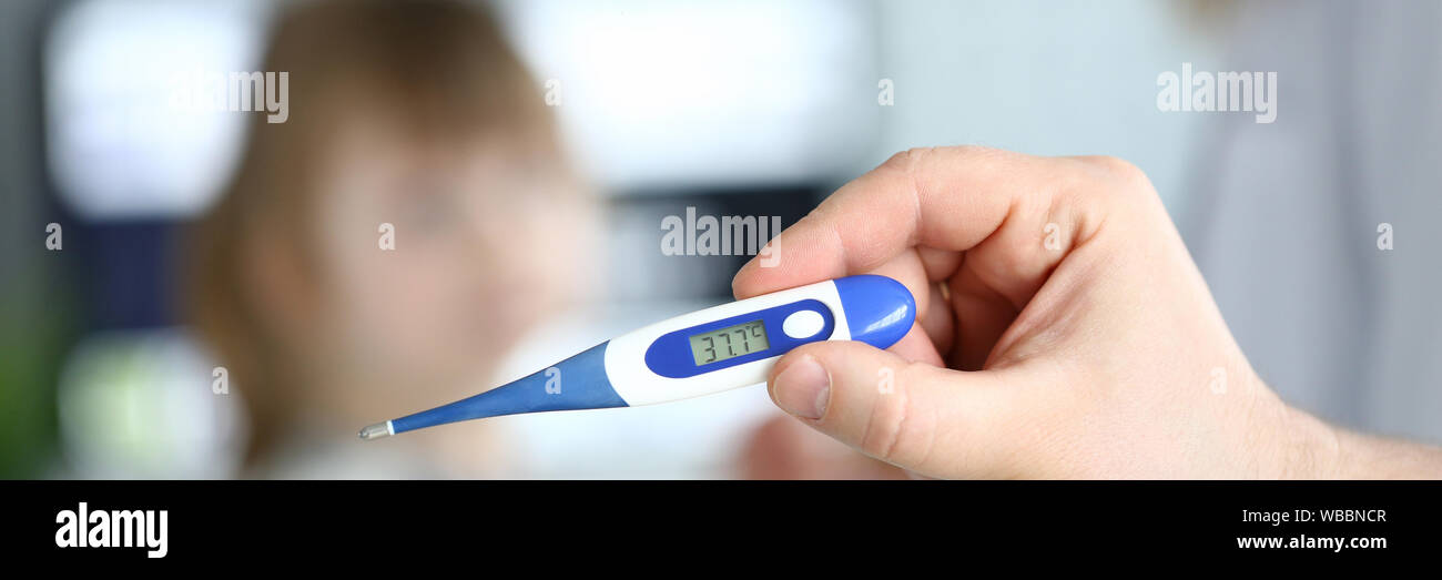 Male arm hold electronic thermometer showing high temperature at child ...