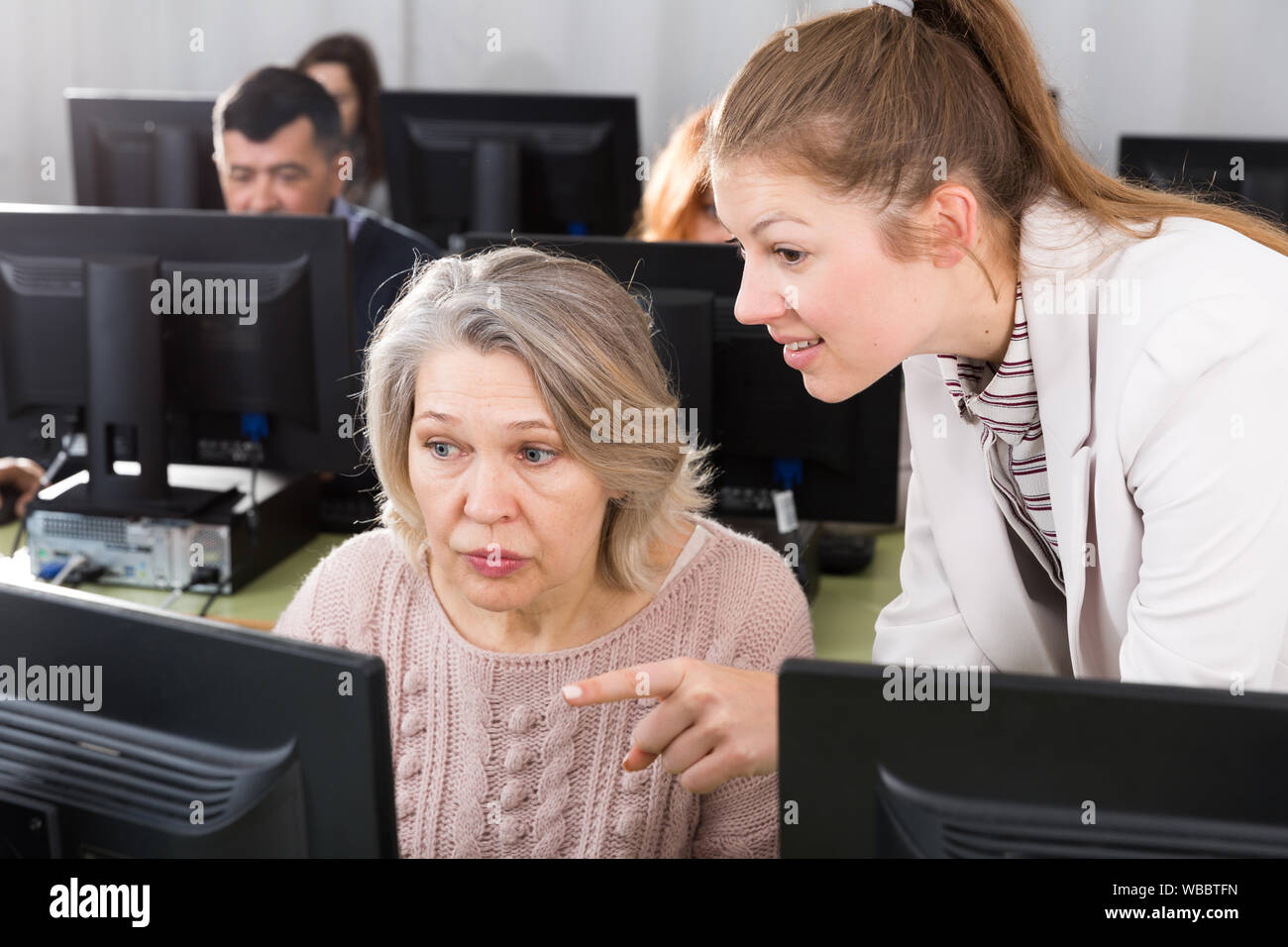 Young business woman explaining something to woman coworker, pointing ...