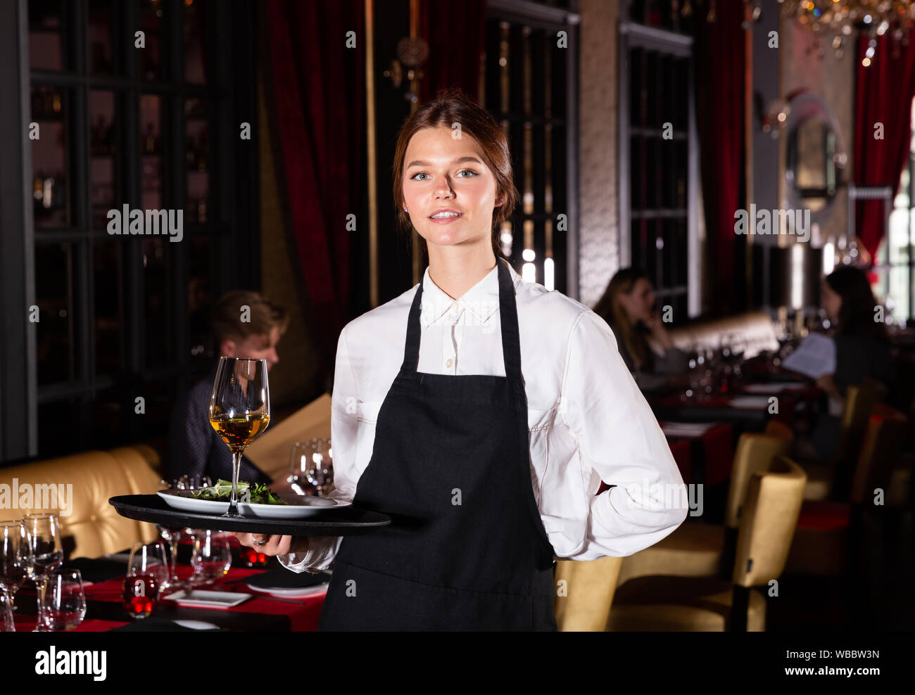 Female waiter standing with serving tray, recommending dishes in ...