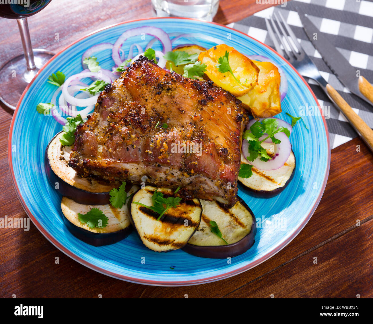 Baked pork rib served with potato and grilled eggplants on plate Stock ...