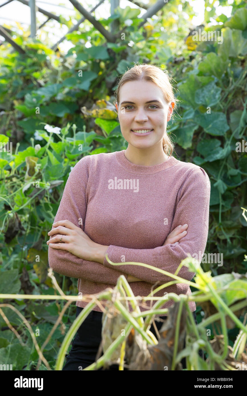 Portrait of young woman on background of organic zucchini plantation ...