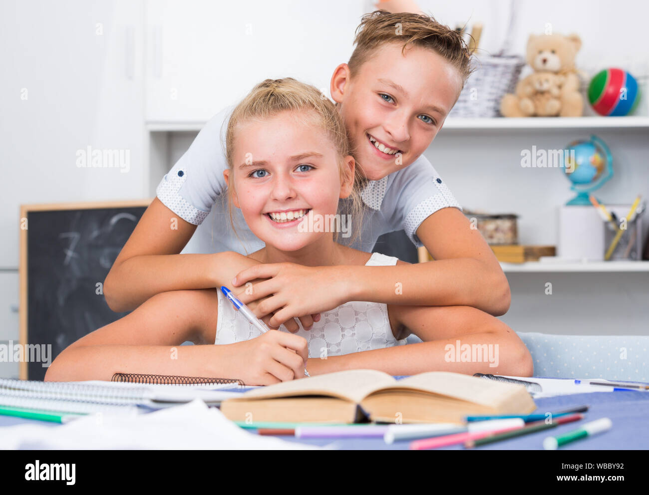 Boy is helping girl doing homework at home Stock Photo - Alamy