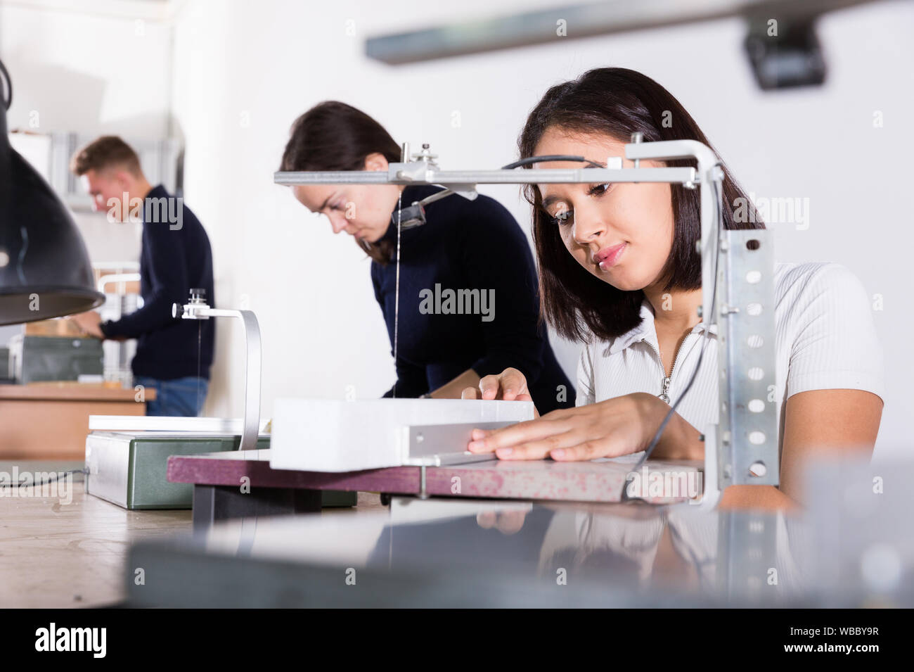 Female student of architecture faculty using scroll saw while engaged ... Female student of architecture faculty using scroll saw while engaged ...