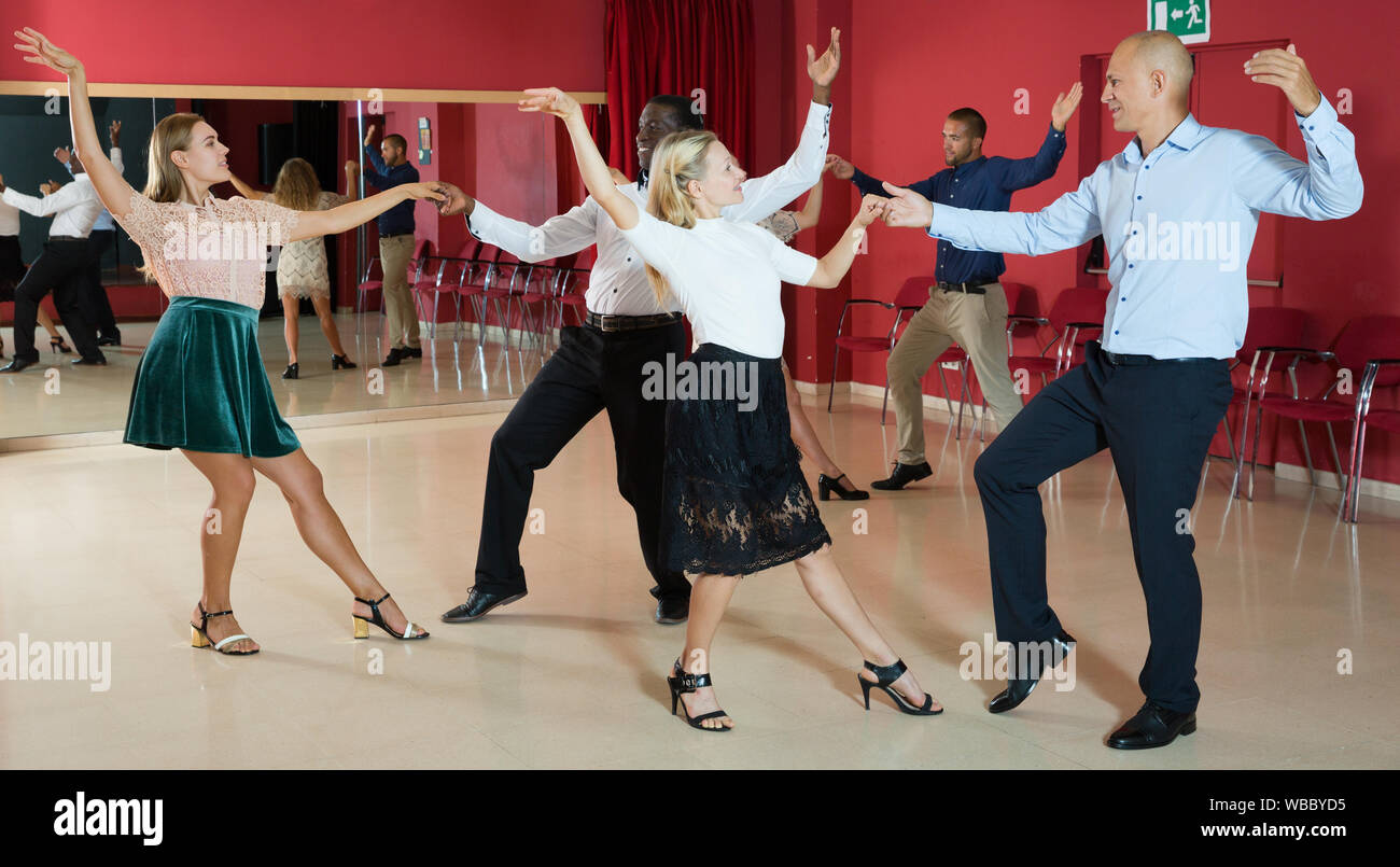 Young smiling people practicing vigorous jive movements in dance class ...
