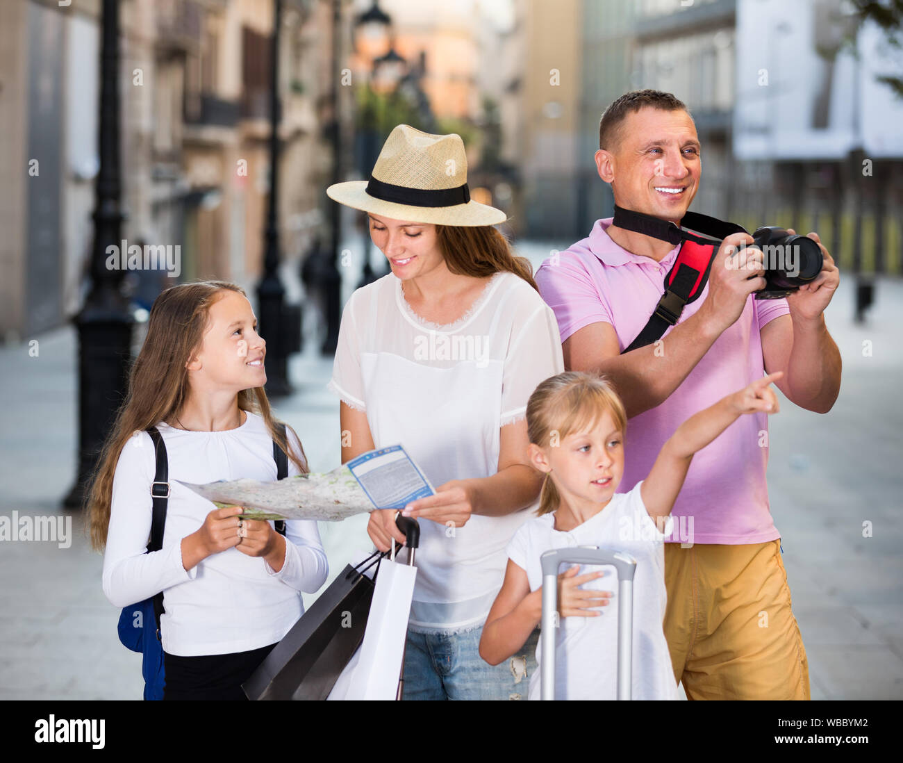 Positive parents tourists with children using camera and map during ...