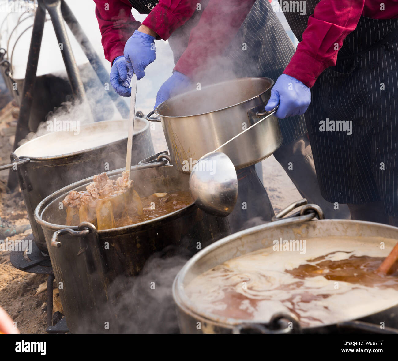 Traditional cooking in iron cauldrons hanging over open fire on ...