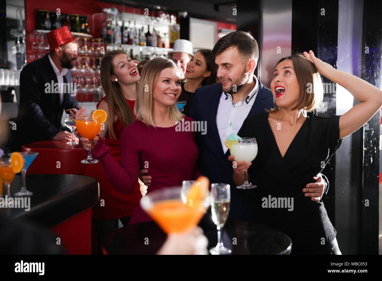 Young man and two women with cocktails having fun at nightclub Stock ...