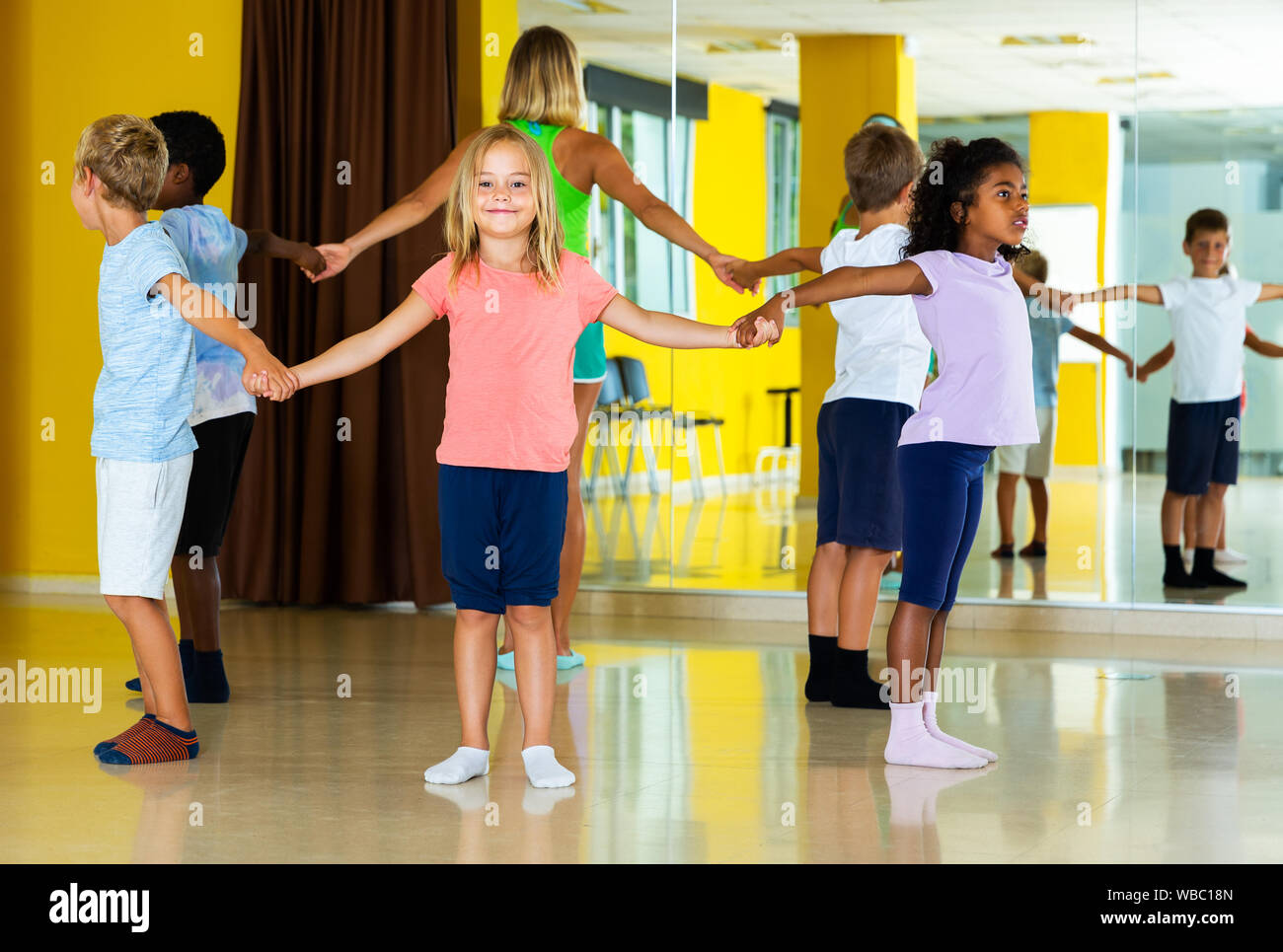 Group of children with their teacher holding hands and dancing in ...
