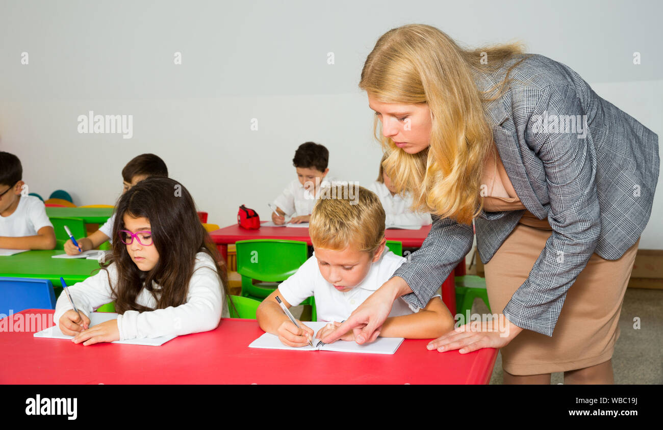 Female teacher helping schoolchildren doing their task in classroom ...