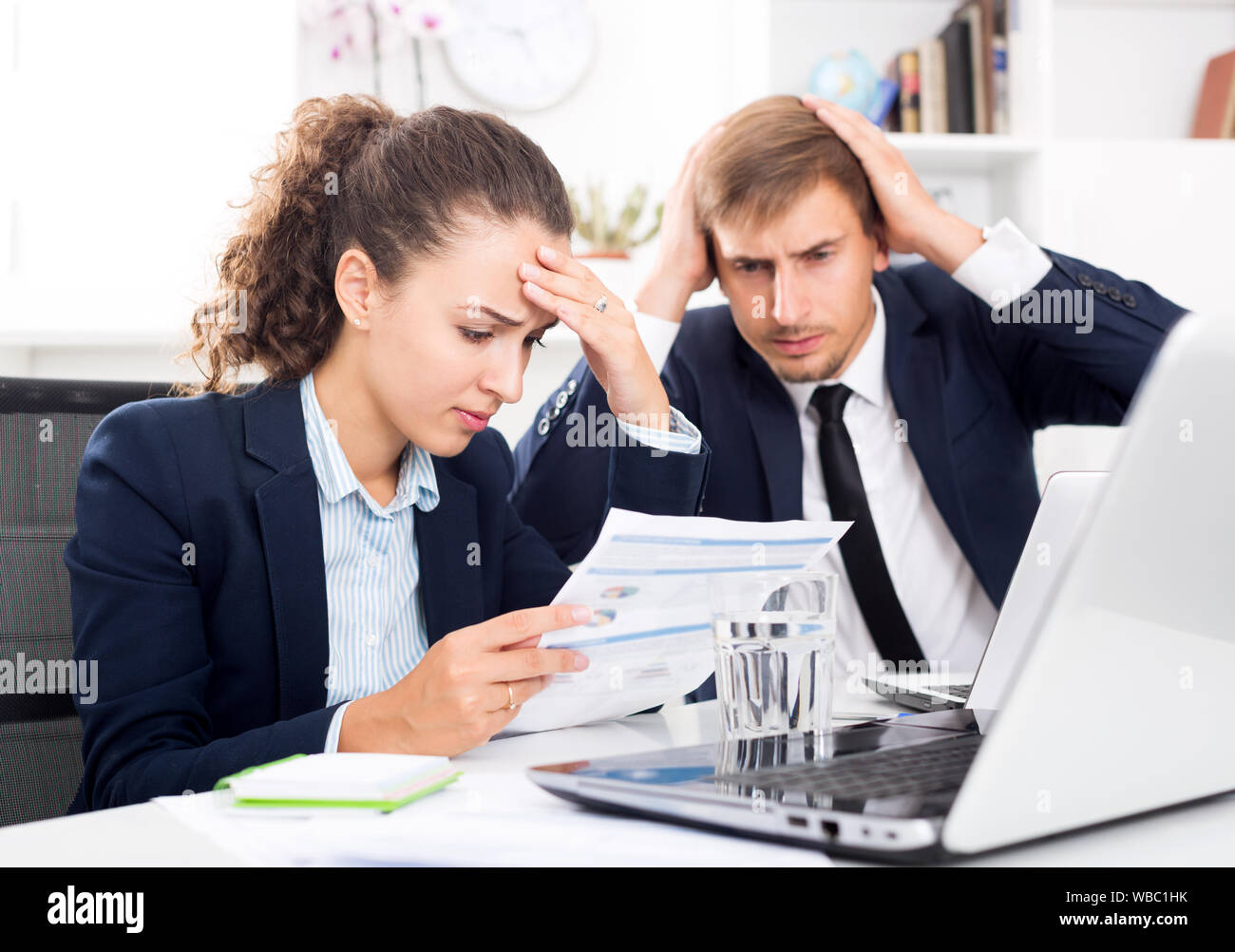 Two depressed business male and young female assistants making mistake ...