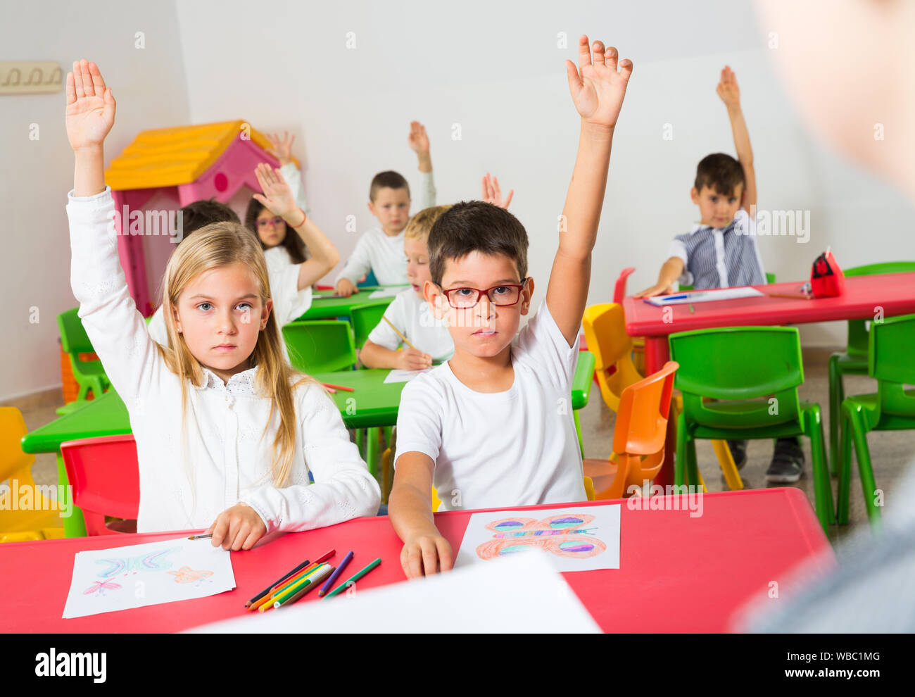 Schoolchildren raising hands in class hi-res stock photography and ...