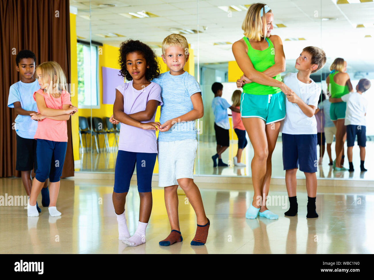 Group of happy smiling children practicing vigorous jive movements in ...