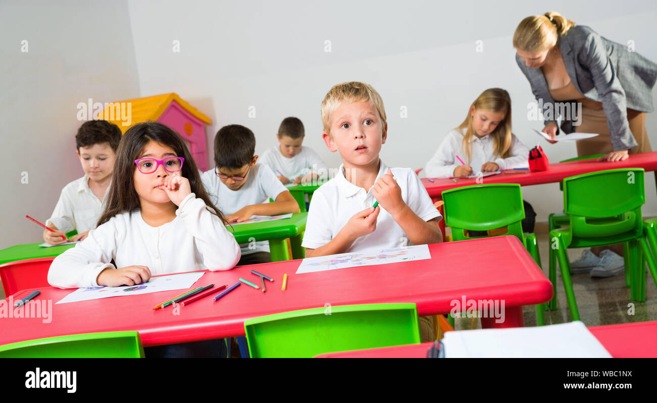 Happy cheerful positive smiling female teacher helping schoolkids ...