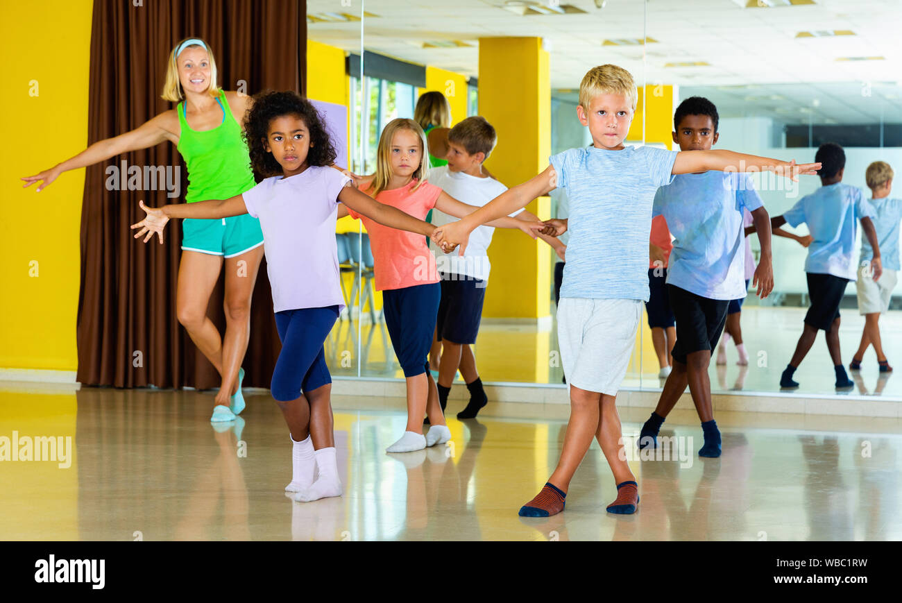 Group of glad cheerful smiling children practicing vigorous jive ...