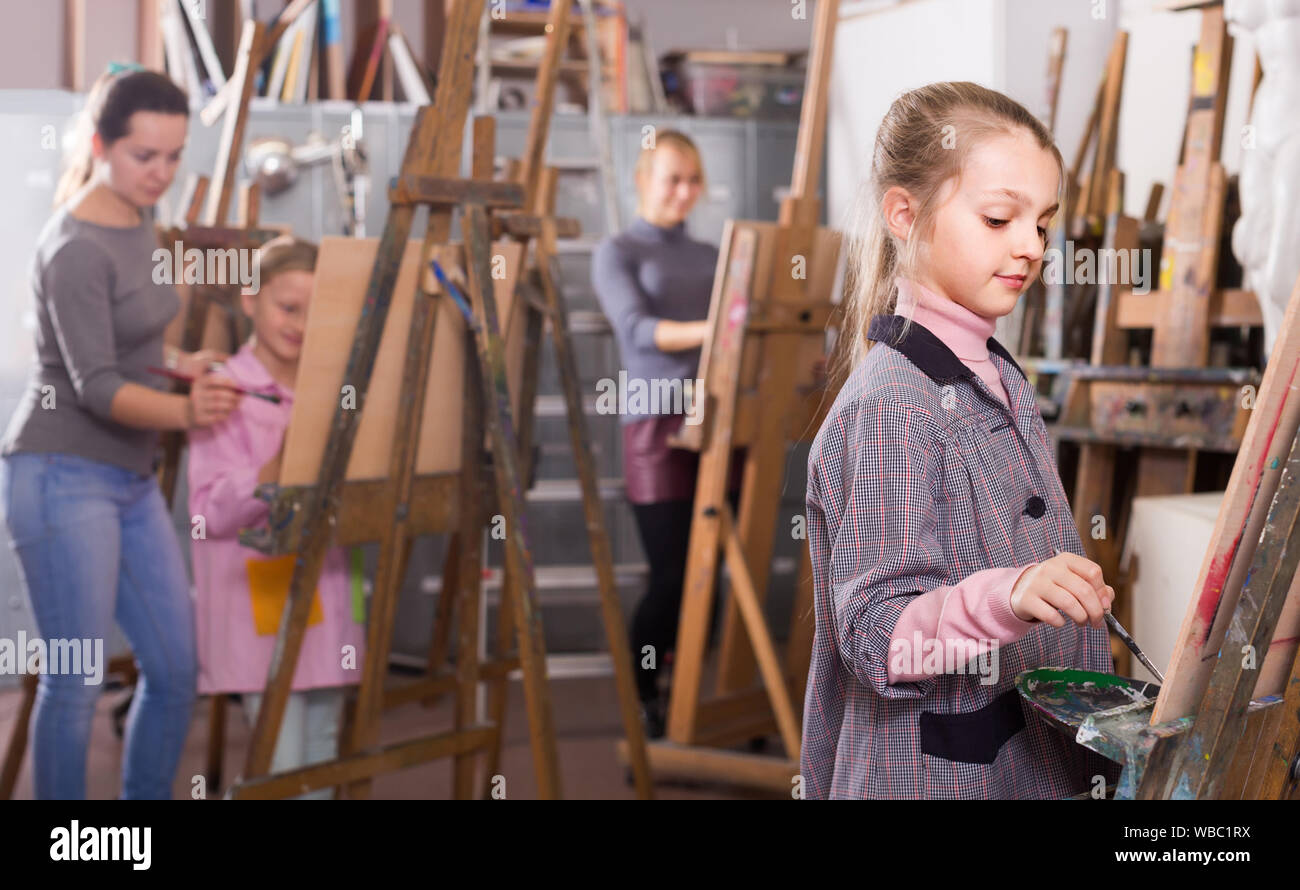Smiling russian schoolgirls diligently training their painting skills ...