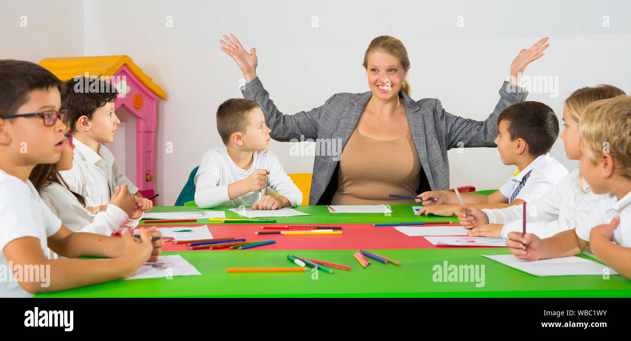 Group of schoolkids drawing in circle with their cheerful female ...