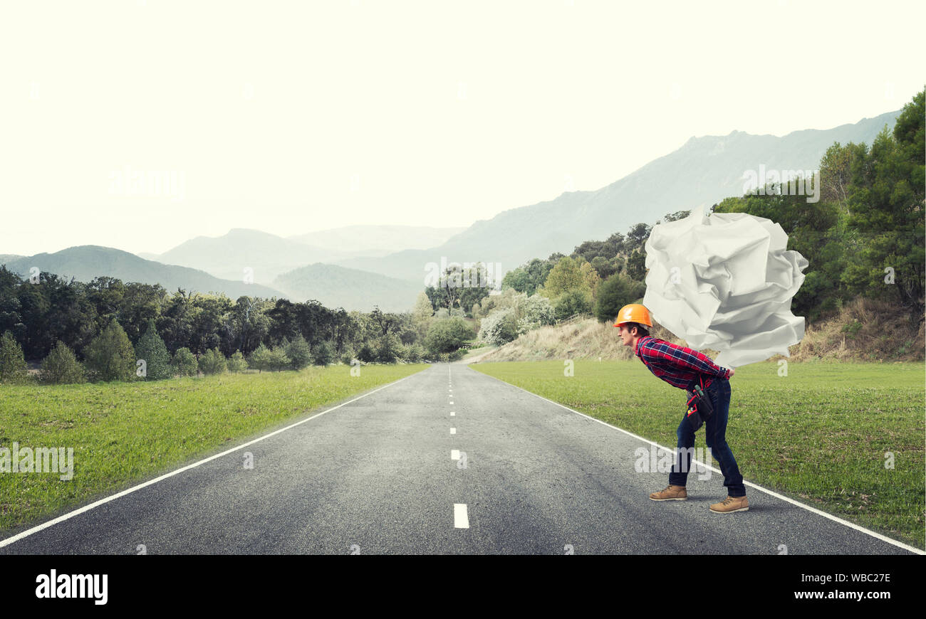 Builder man carrying paper ball on his back Stock Photo - Alamy