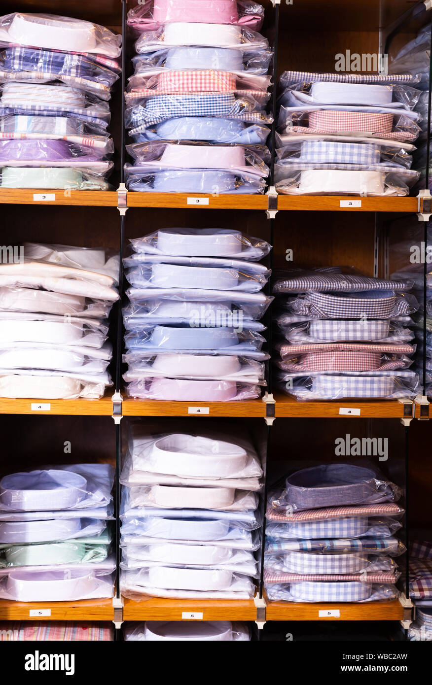 Large assortment of shirts displayed on shelves in men clothes shop ...