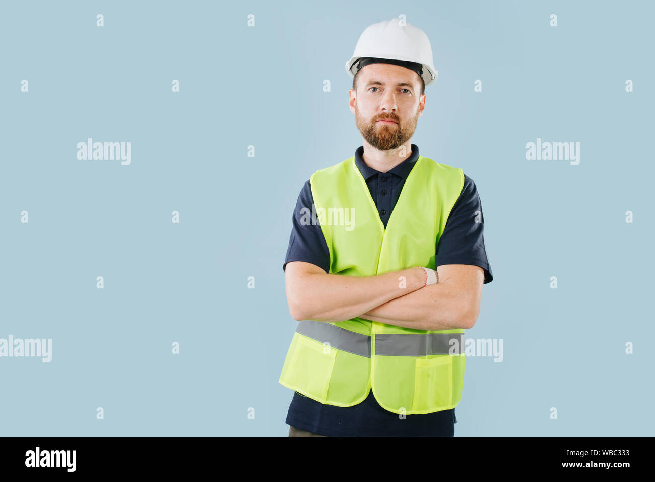 Confident construction worker in a white helmet and yellow safety vest ...