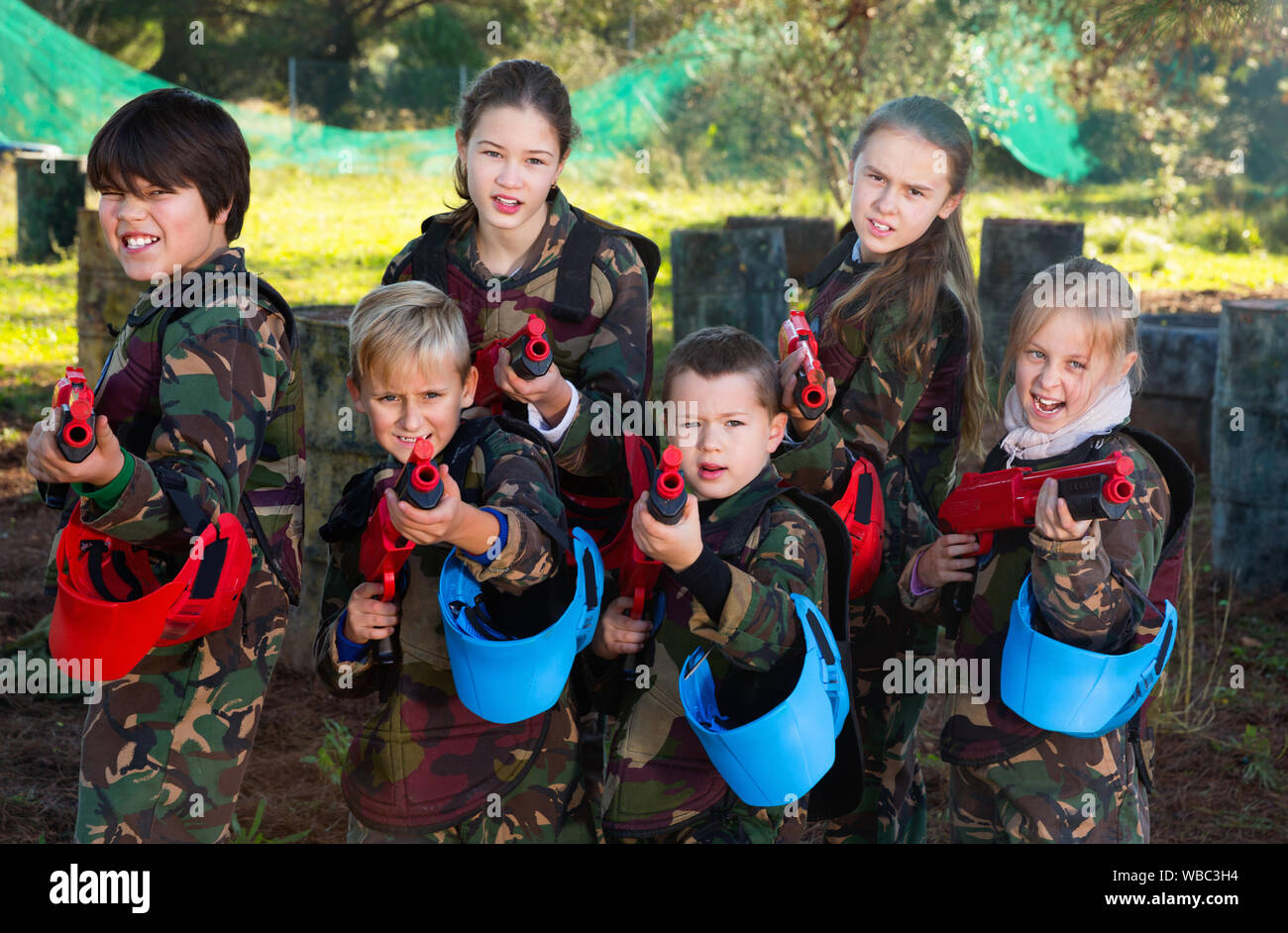 Friendly happy smiling group of children paintball players in ...