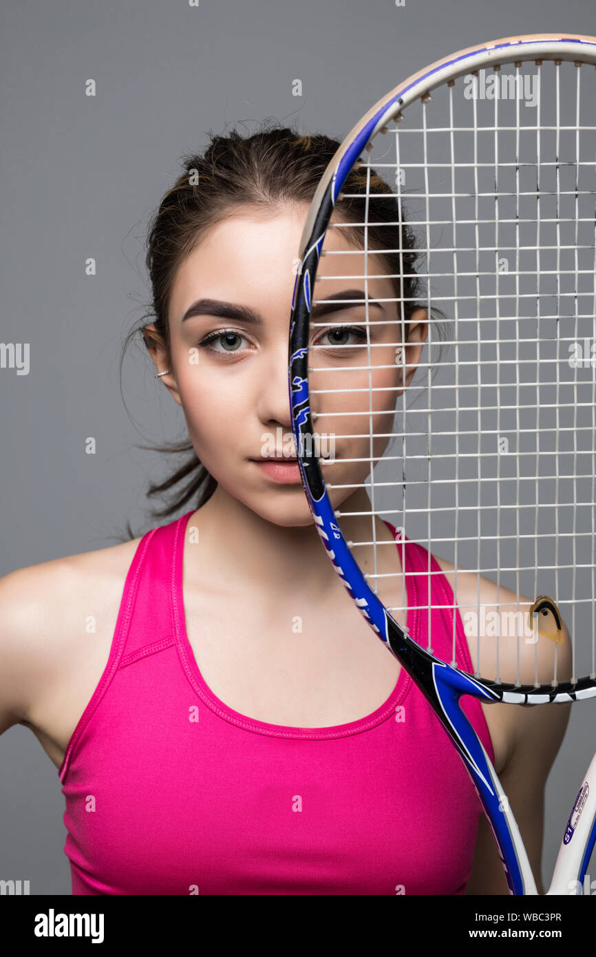 Woman with a tennis racket over her face. Neutral face and confident ...