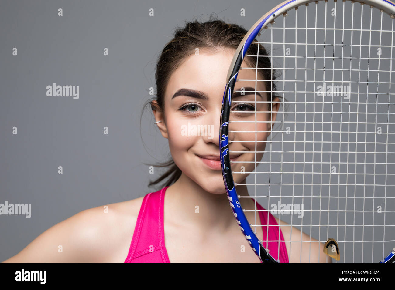 Woman with a tennis racket over her face. Neutral face and confident ...