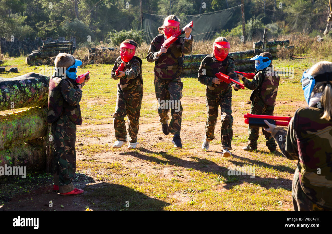 Teams of active kids facing on battlefield in outdoor paintball arena ...