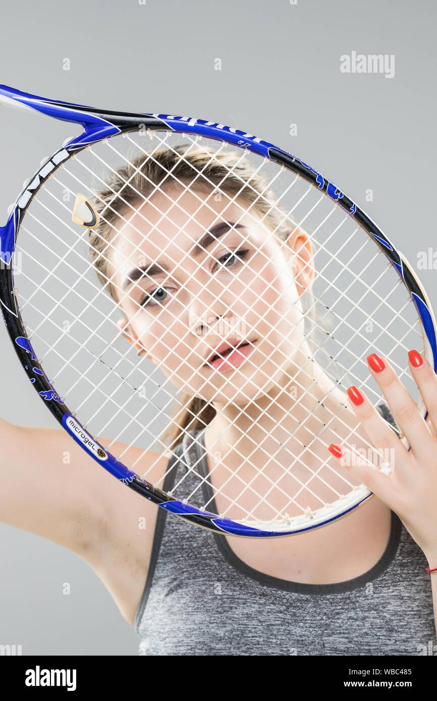 Woman with a tennis racket over her face. Neutral face and confident ...