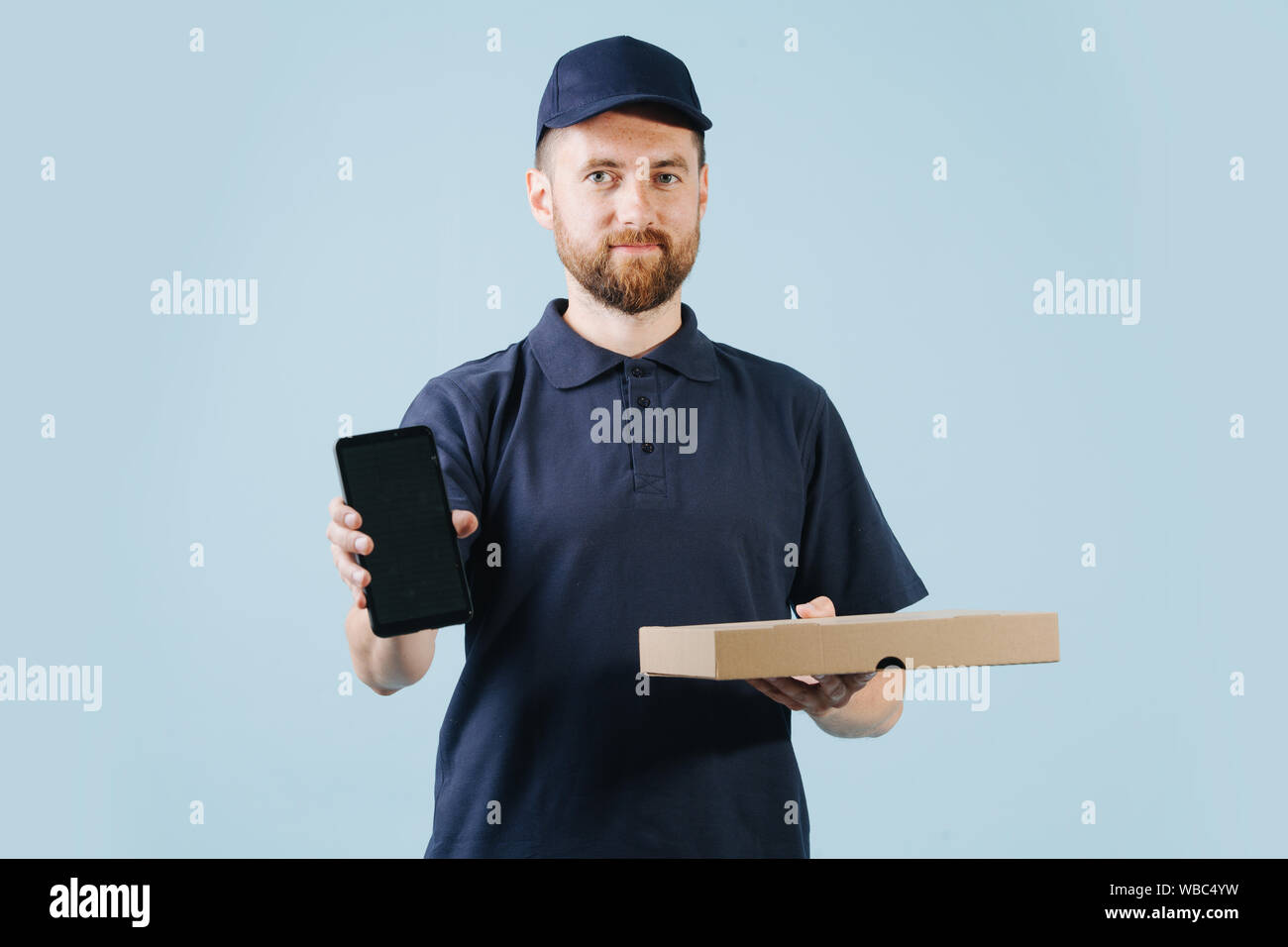 Courier is delivering pizza, holding smart phone in a hand for customer ...