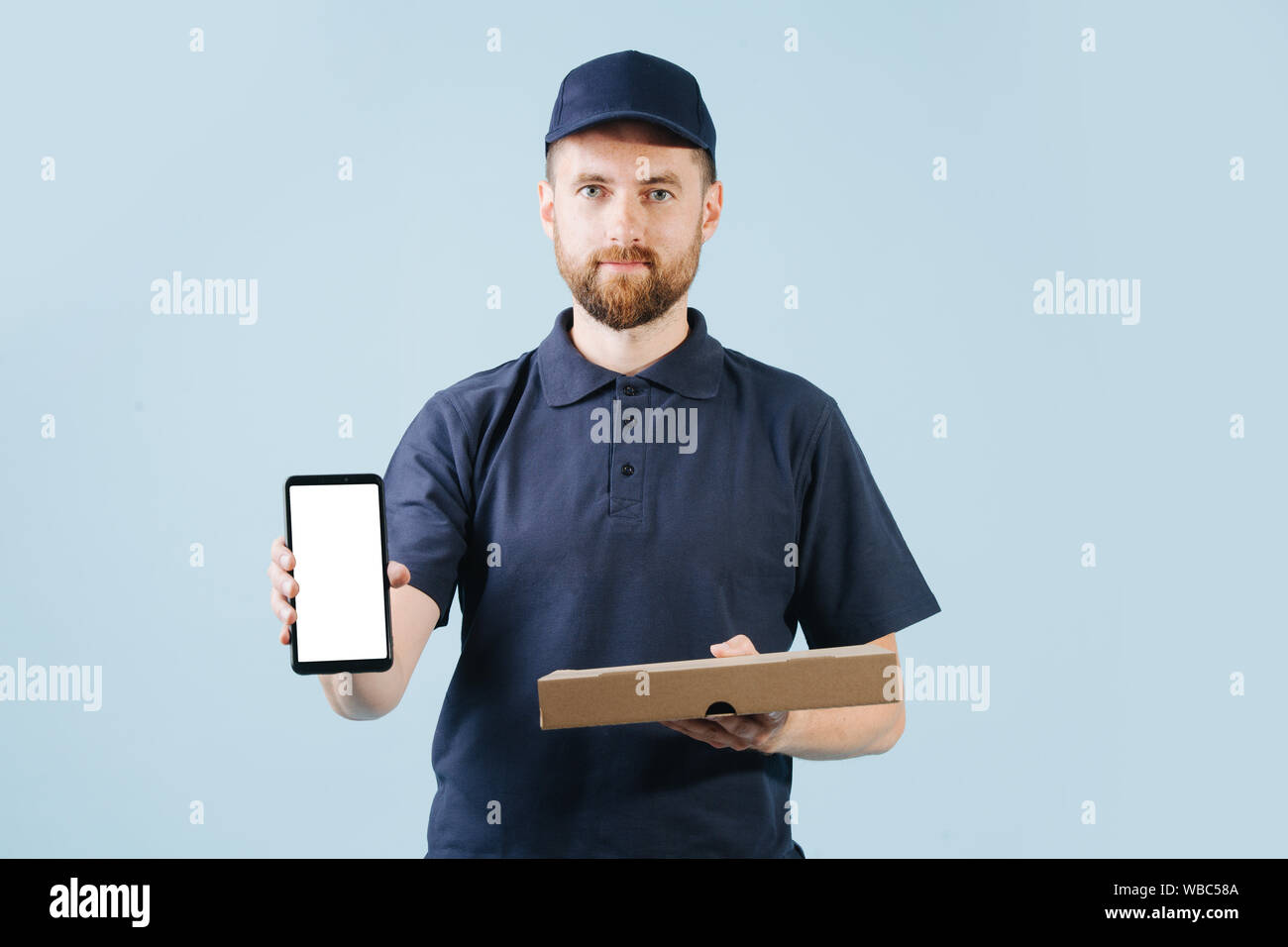 Courier is delivering pizza, holding smart phone in a hand for customer ...