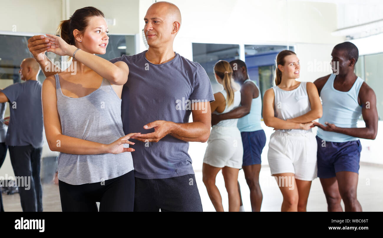 Multiracial dancing couples enjoying latin dances in modern studio ...