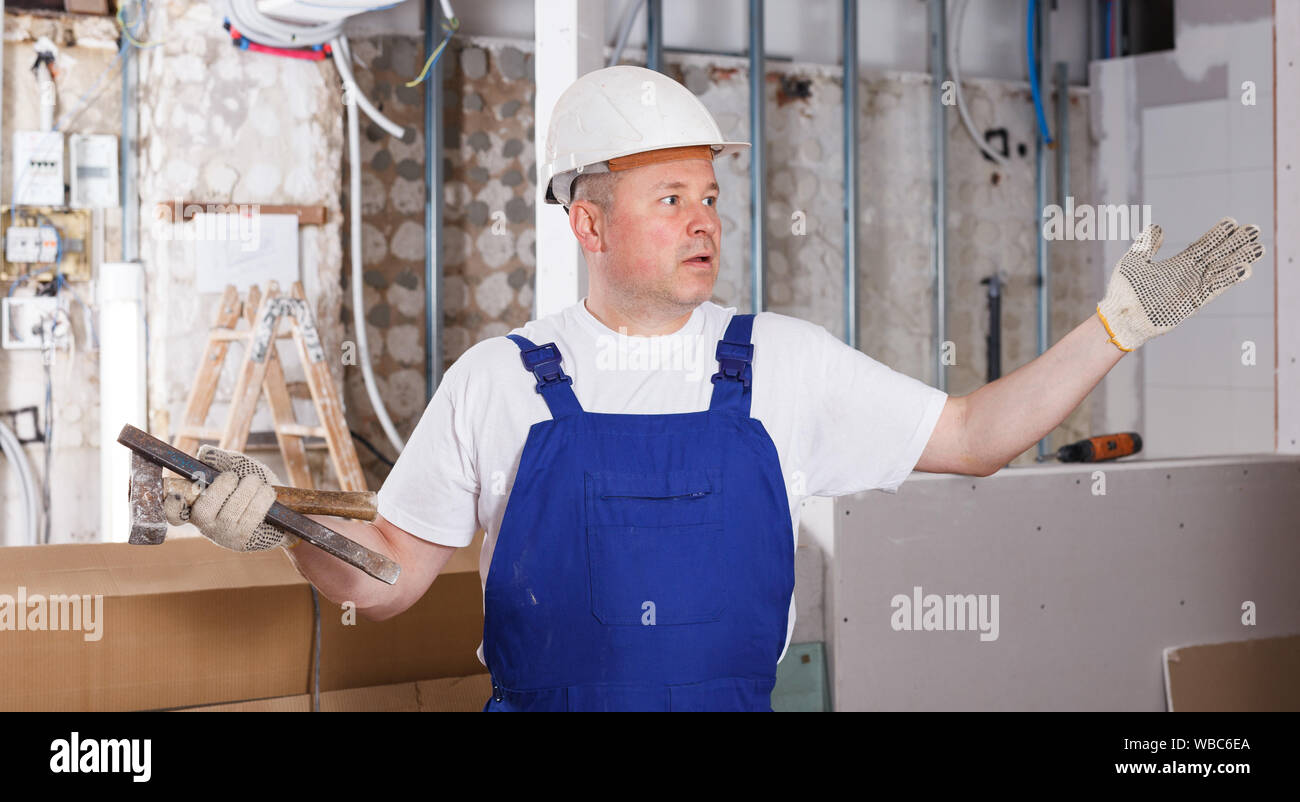 Scared and confused male contractor looking at room and determining ...