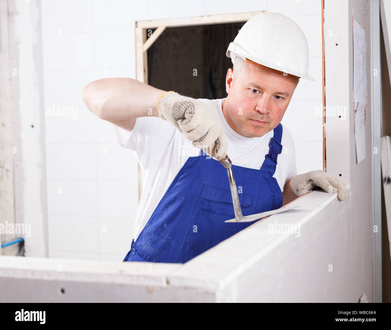 Professional plasterer taping drywall joints with spatula and plaster ...