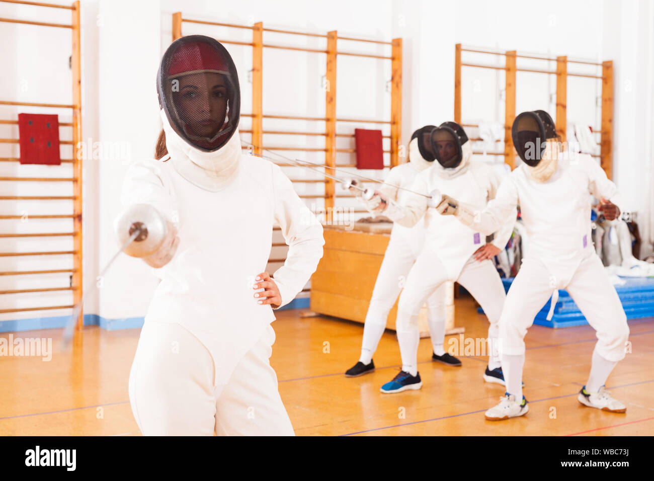 active woman fencer practicing fencing combination in training room ...