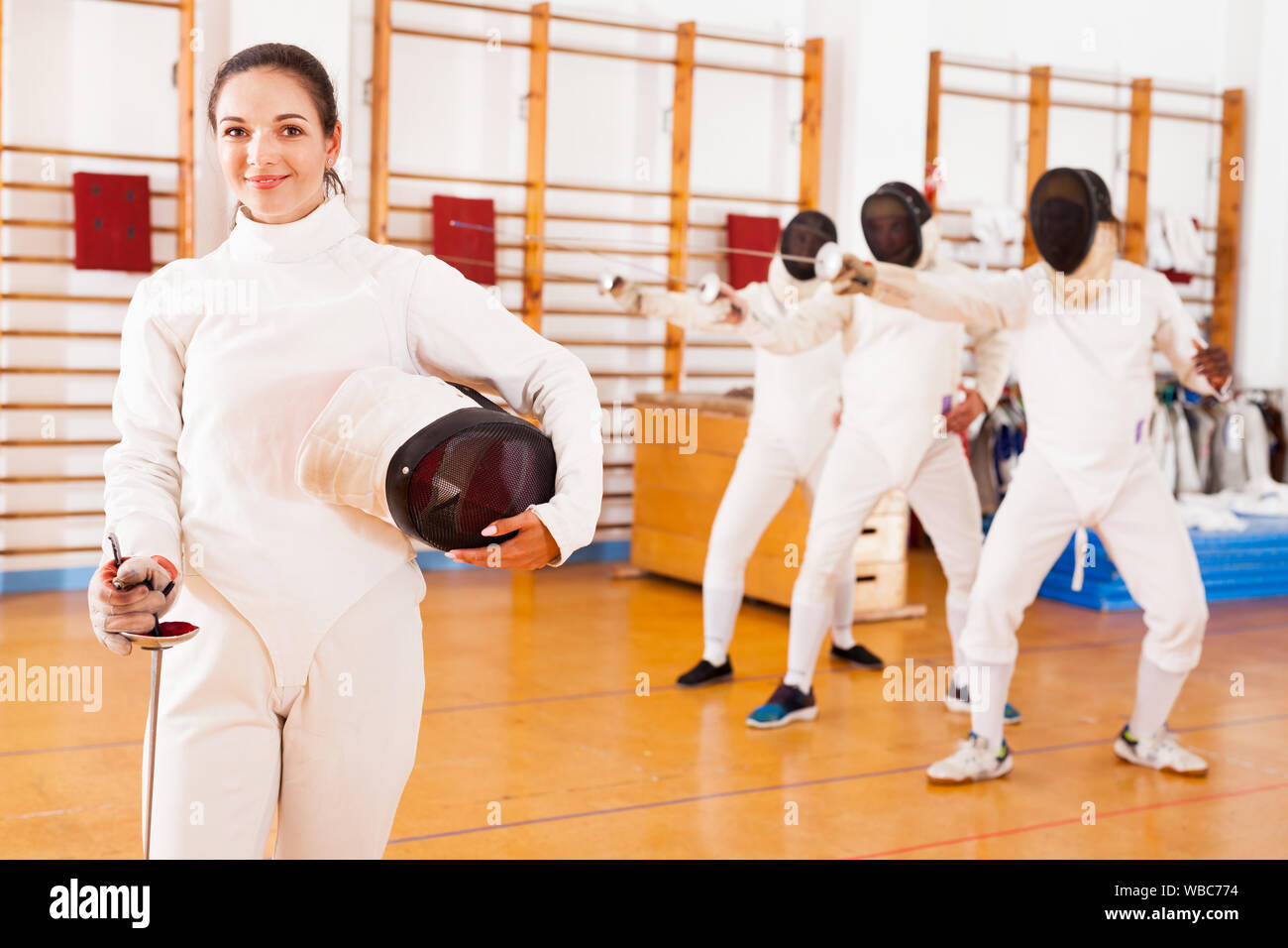 Positive active young female fencer standing at fencing workout Stock ...