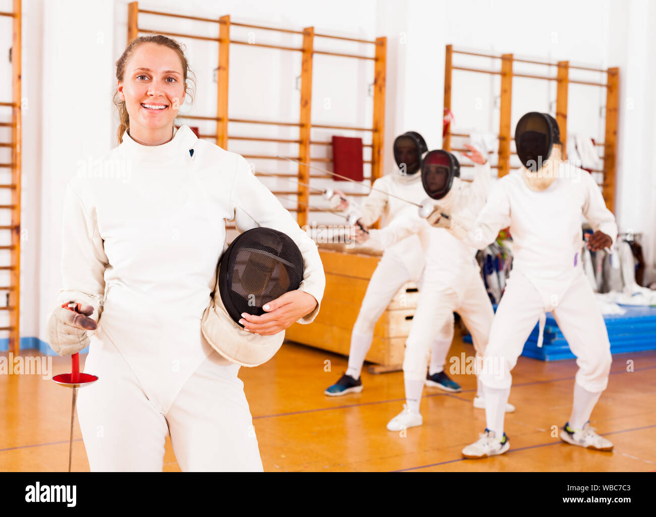 Positive active young female fencer standing at the fencing workout ...