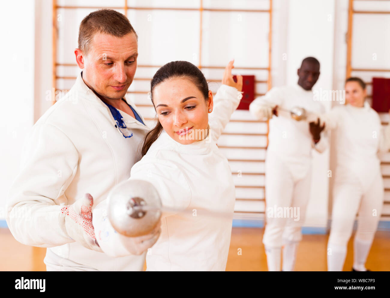 Woman fencer practicing new movements with trainer at fencing room ...